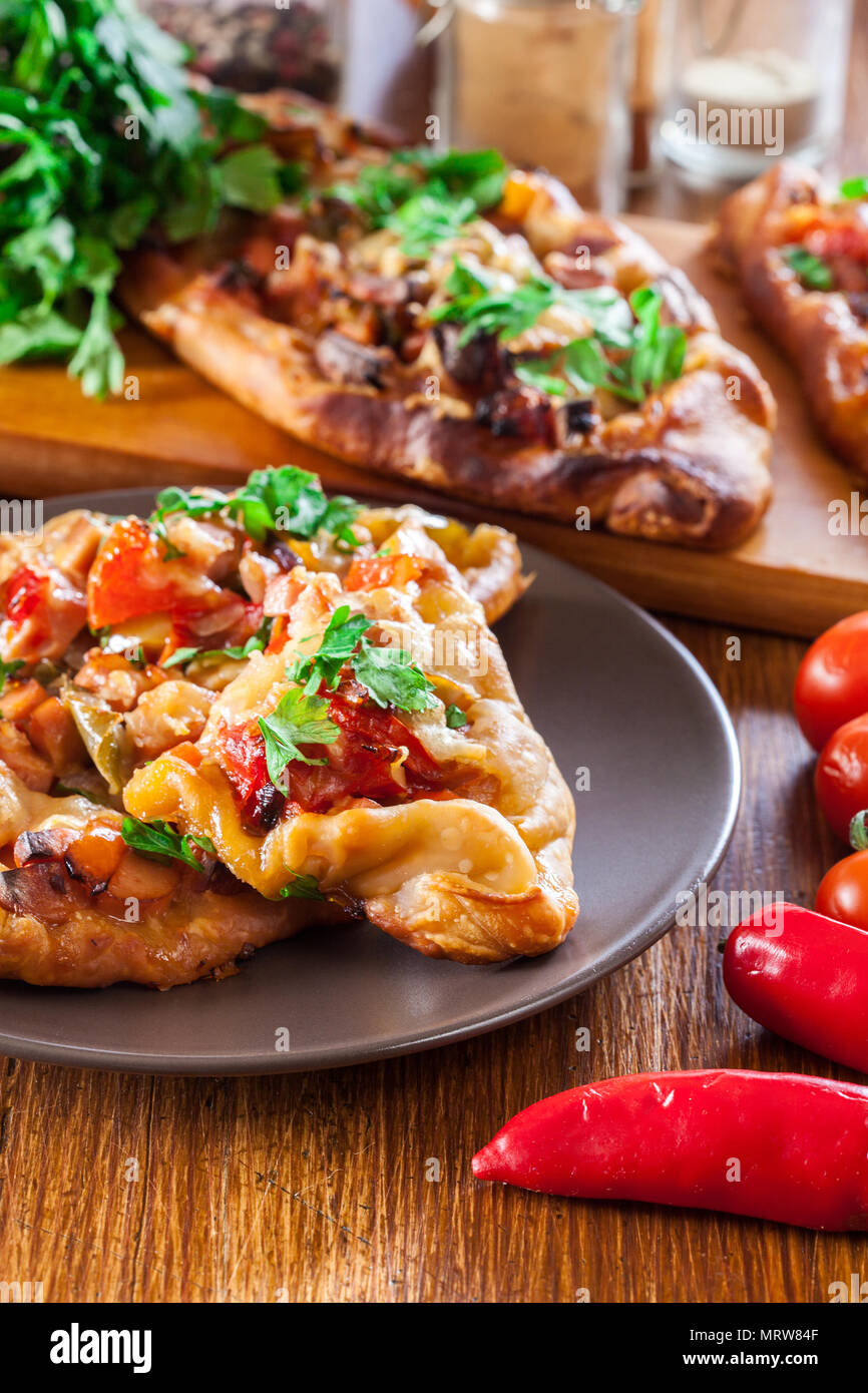 Sliced traditional Turkish pide with meat and vegetables on a plate ...