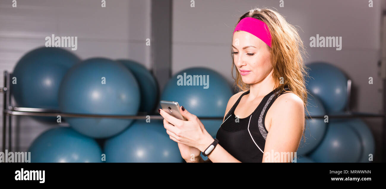 Attractive woman using cell phone and fitness tracker in gym Stock ...