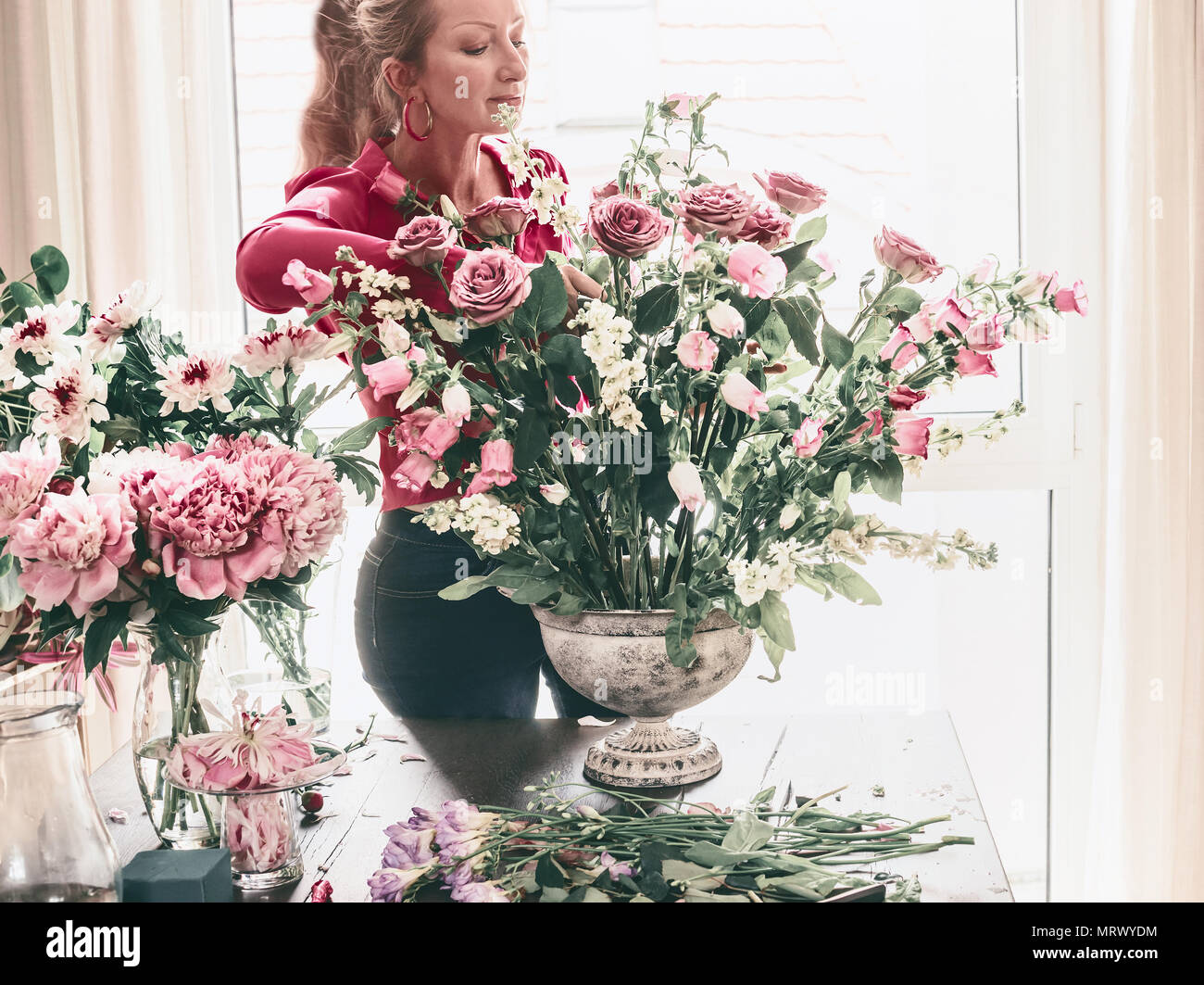 Happy florist women arranging great festive flowers bouquet with urn ...