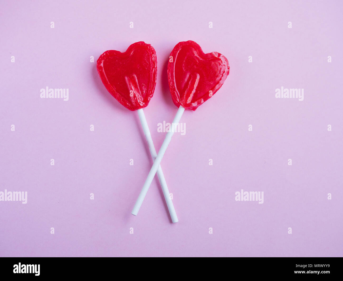 Two red heart lollipop on pink background Stock Photo - Alamy