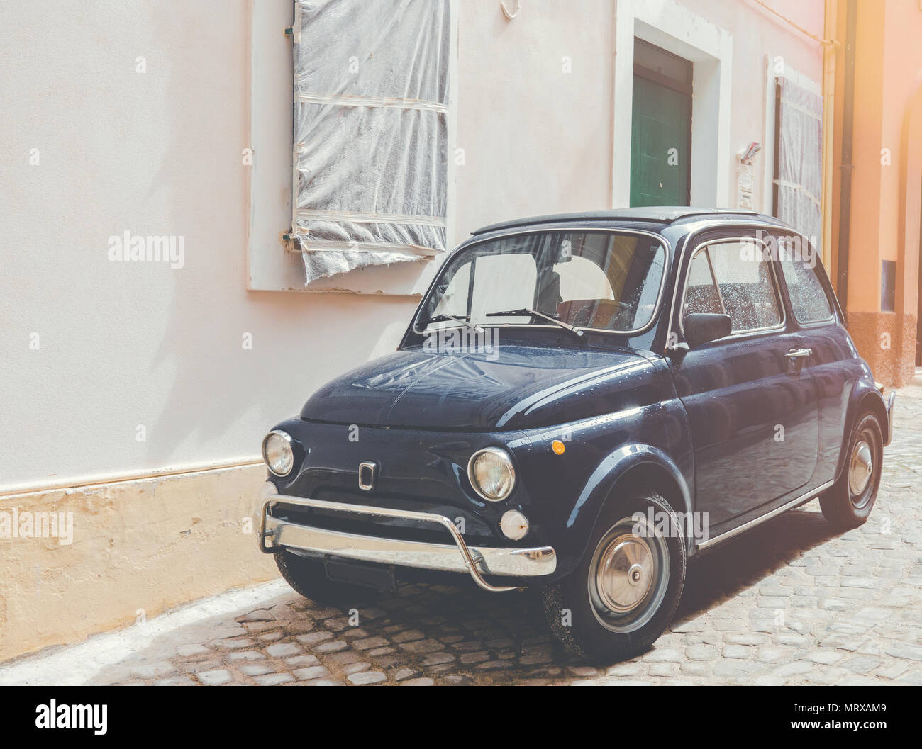 an old blue Italian 500 car is parked on a Italian typical street Stock ...