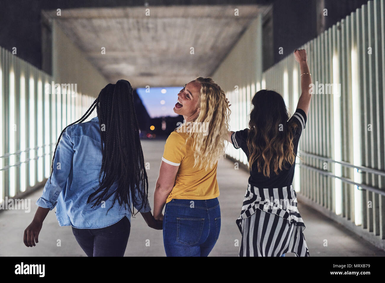 Laughing group of young women having fun while walking hand in hand ...