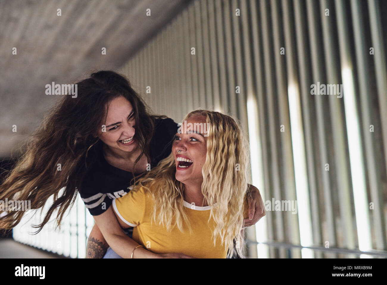 Laughing young woman being carried on her girlfriend's shoulders while ...