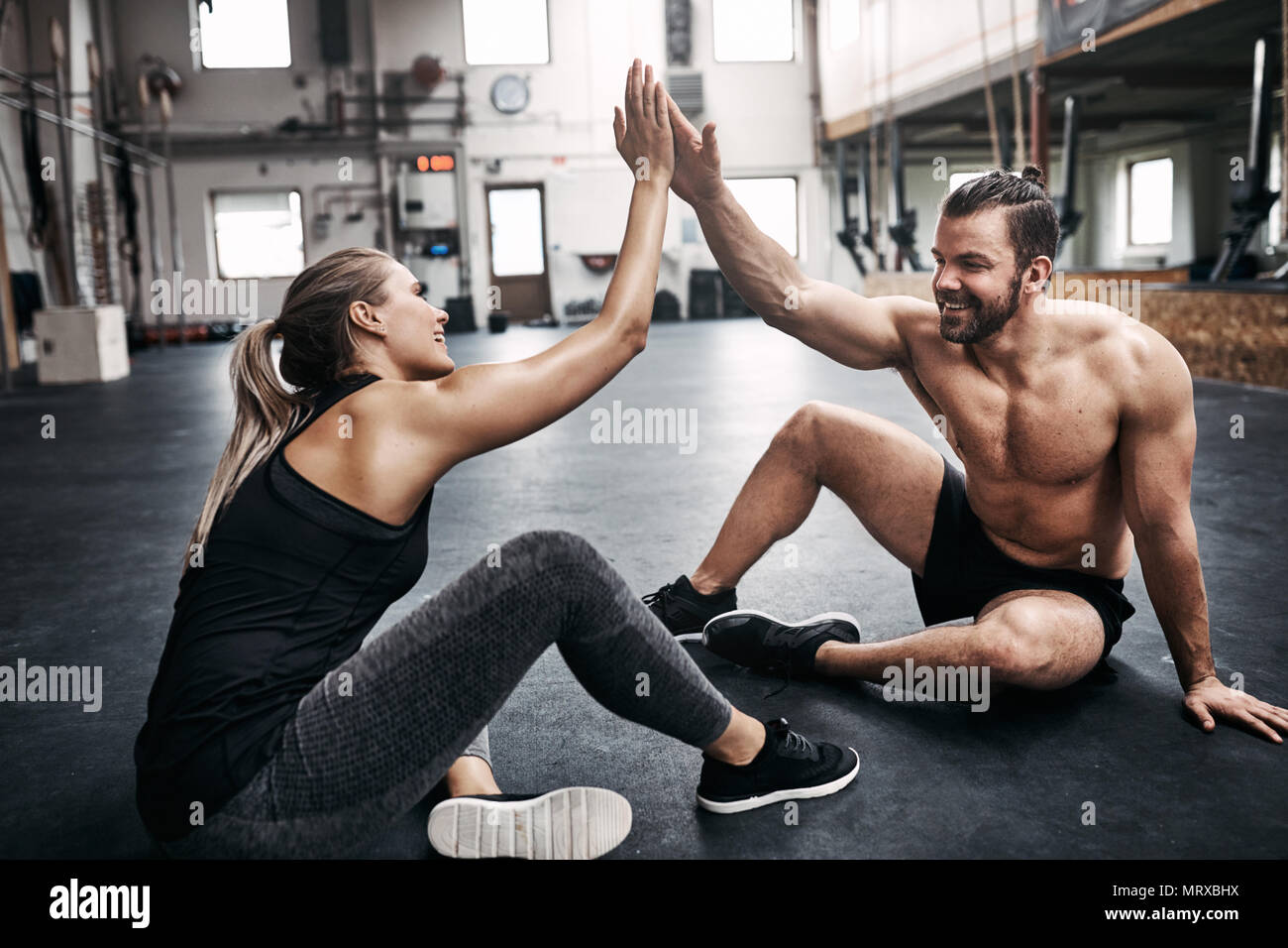 Two fit young people in sportswear smiling and high fiving together ...