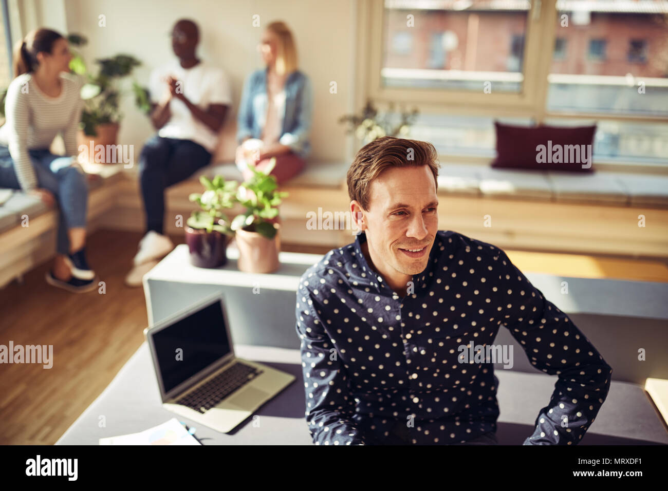 Smiling manager sitting on his desk during a break in an office with ...