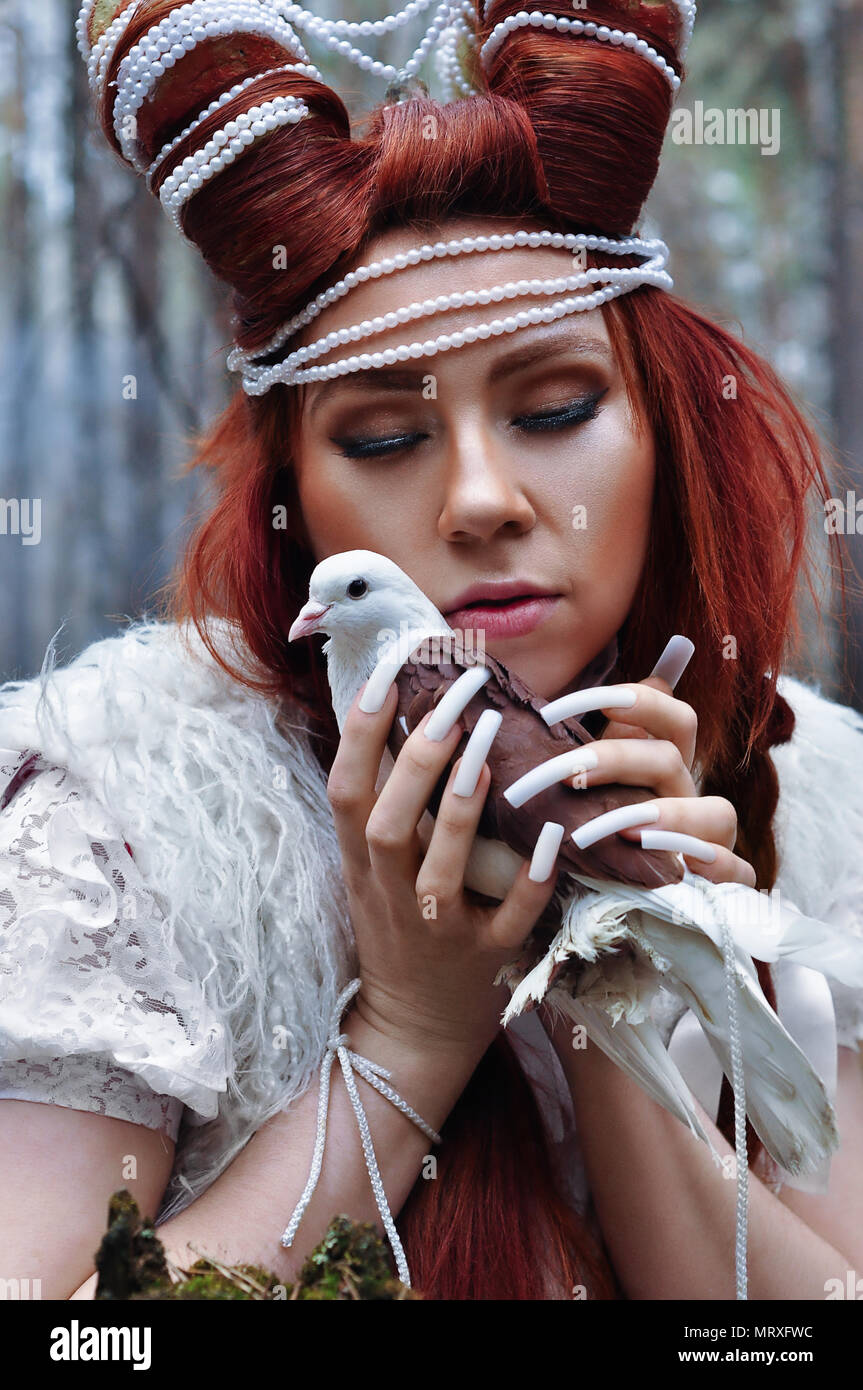 Witch with horns and a magical dove in her hands in the woods Stock ...