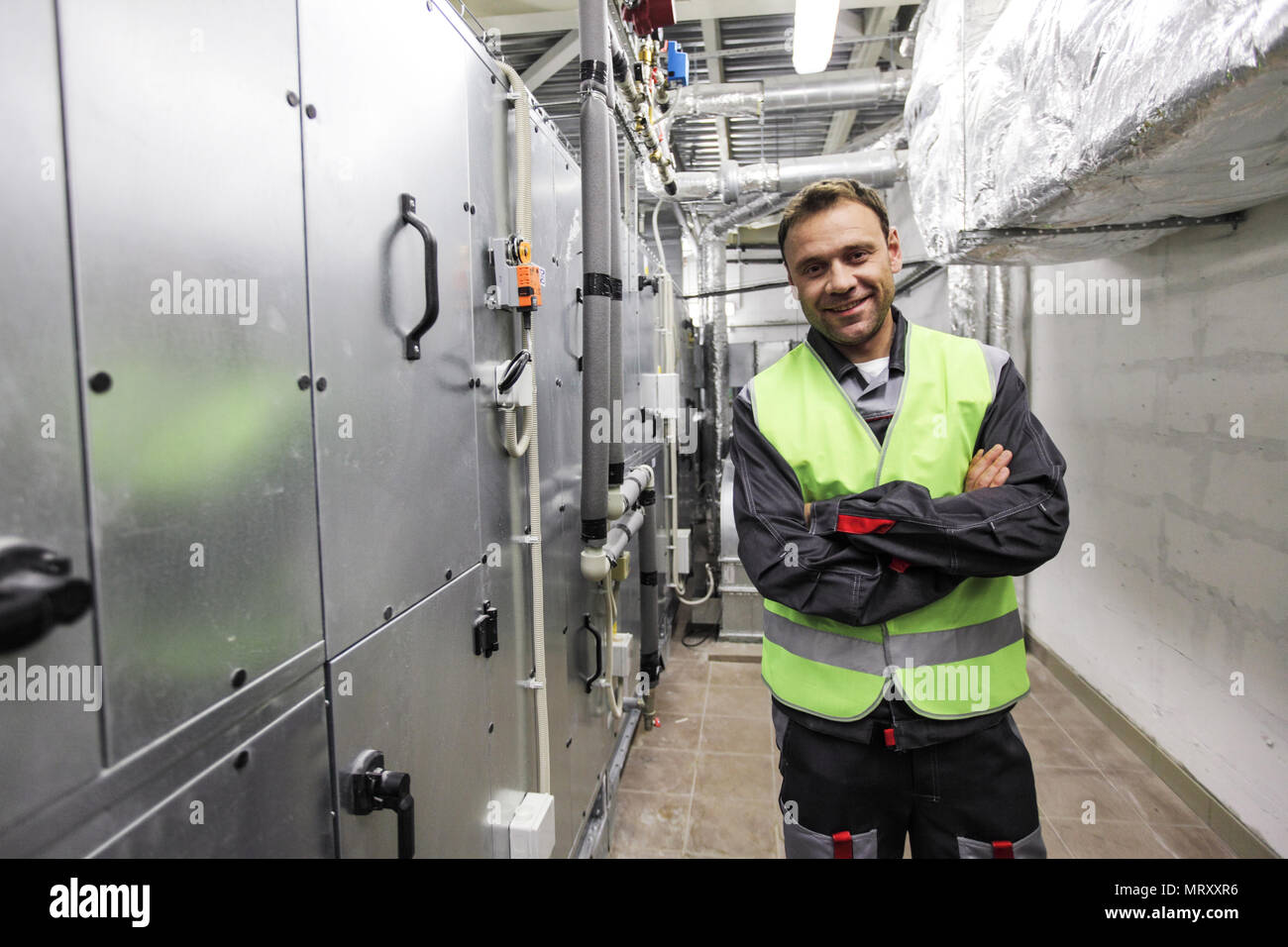 Portrait of smiling worker in electrical switchgear room of CNC plant ...