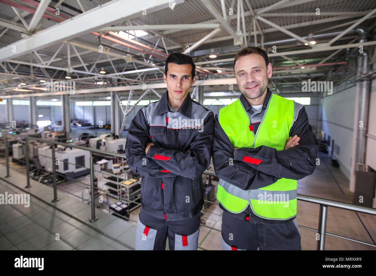 Team of two workers in uniform standing at background of CNC factory ...