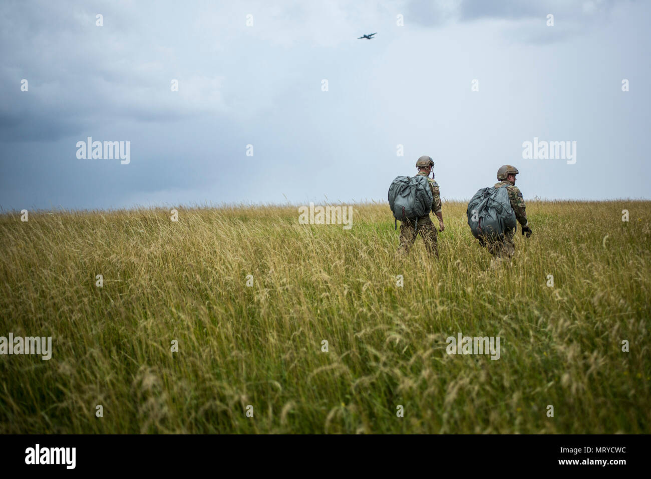U.S. Air Force static-line parachutists carry their parachutes after ...