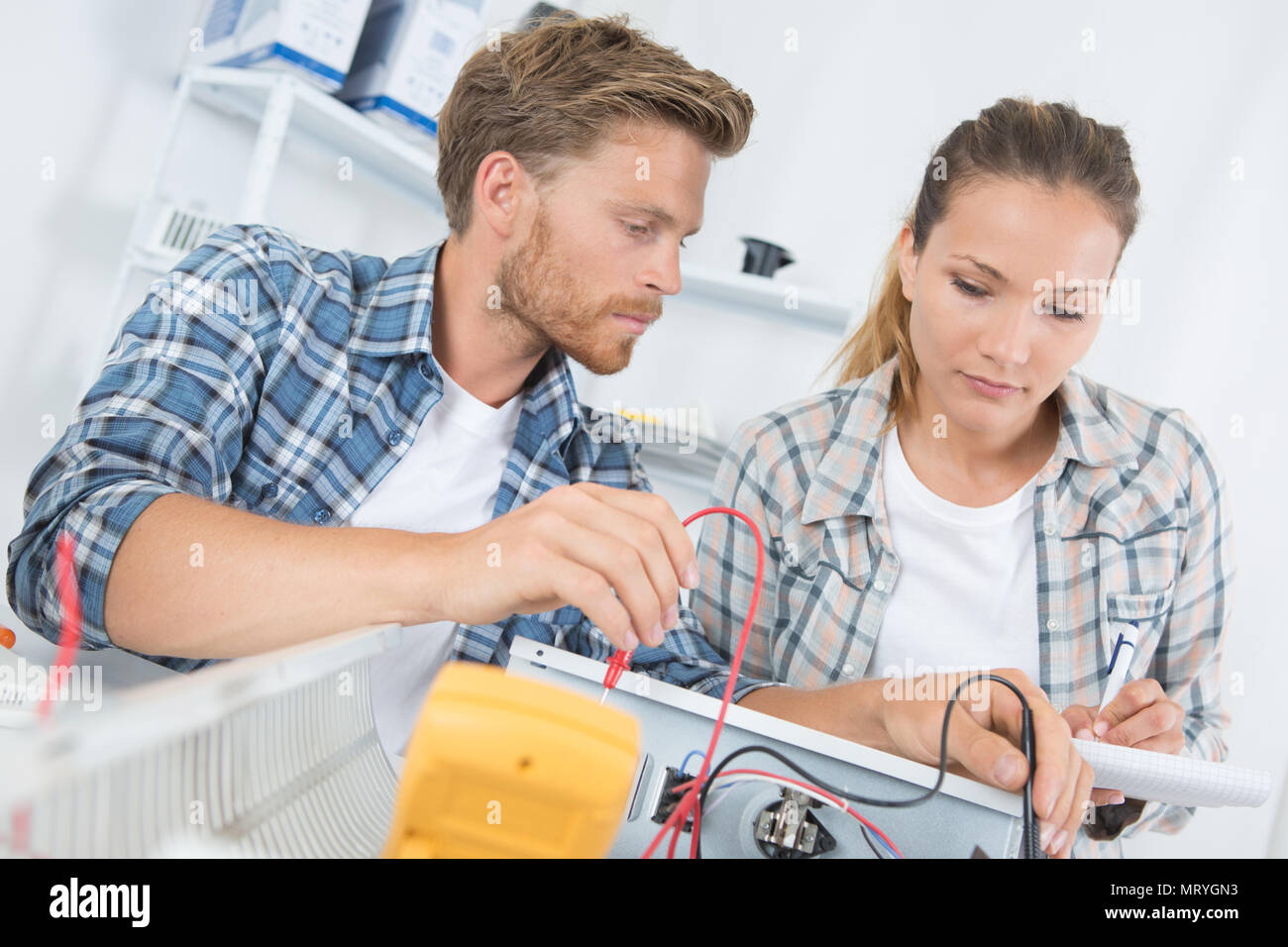 Two technicians testing appliance with multimeter Stock Photo - Alamy