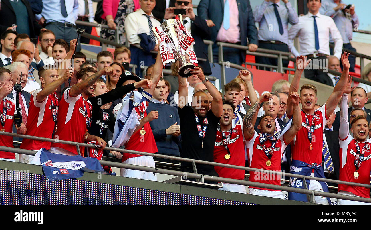 Rotherham United manager Paul Warne lifts the trophy with Richard Woods ...