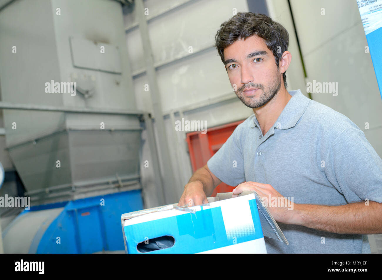 young handsome worker holding carton in factory warehouse Stock Photo ...