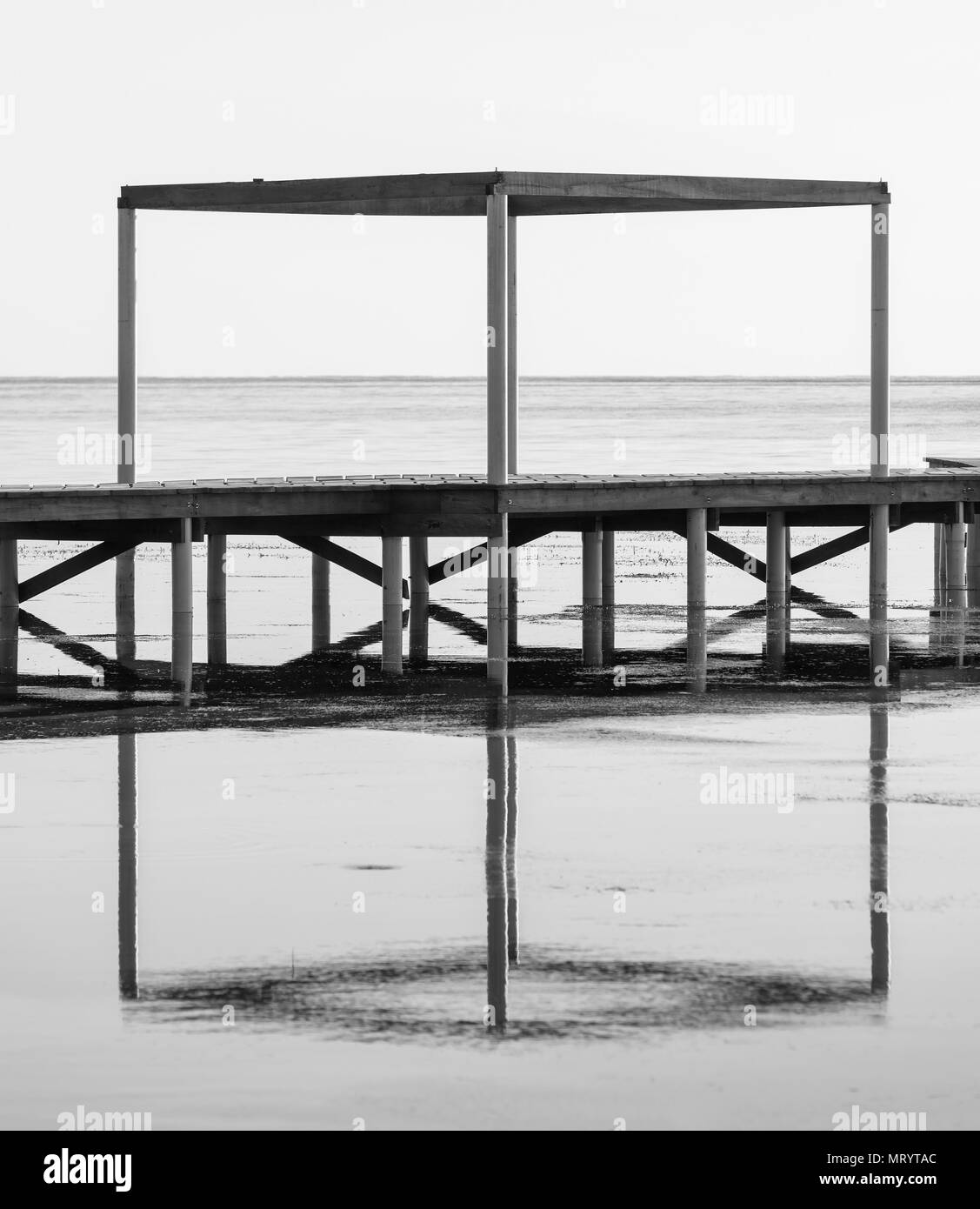 Black and white wooden jetty reflection over water as abstract ...