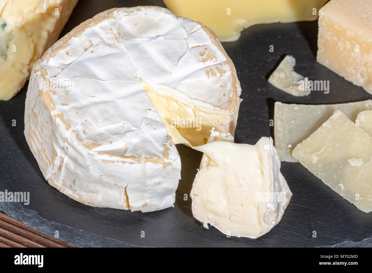 portion of fresh white cheese with mold and various types of cheese on ...