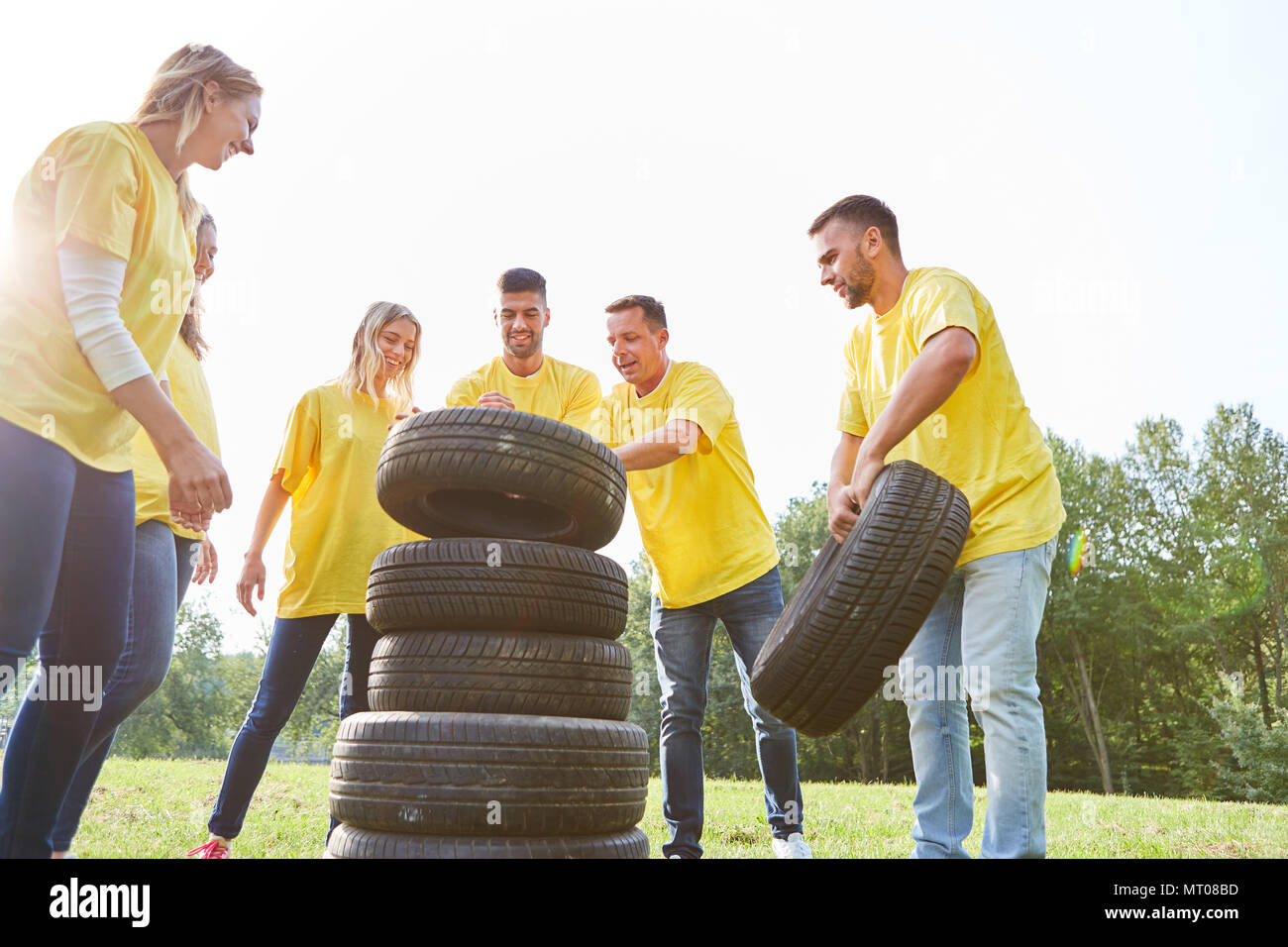 Young people are stacking car tires in teamwork event at a teambuilding ...