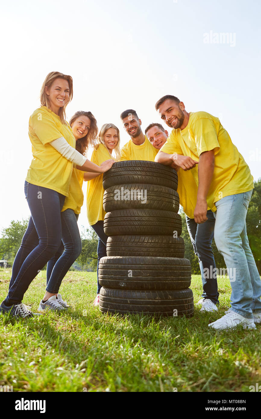 Happy team is standing at a stack of tires in a teambuilding workshop ...