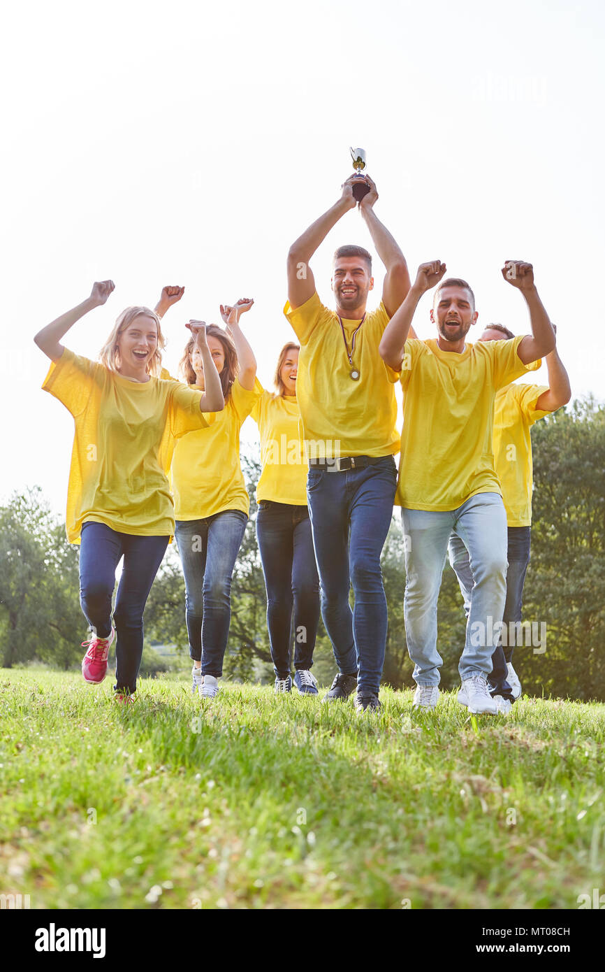 Happy winner team with cup cheers at a team building event in summer ...