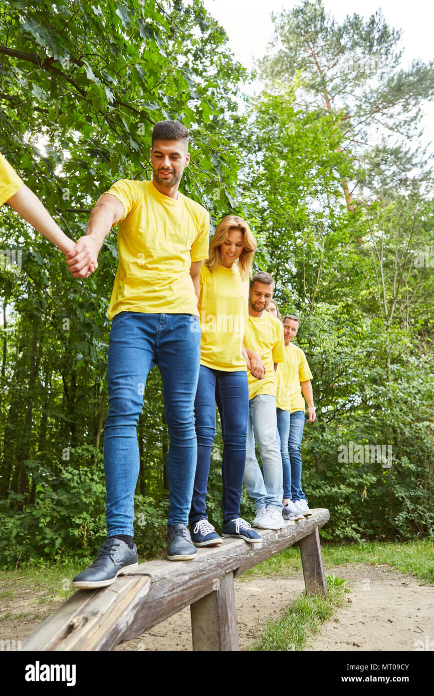 Young team balances together over a beam as a teambuilding exercise ...