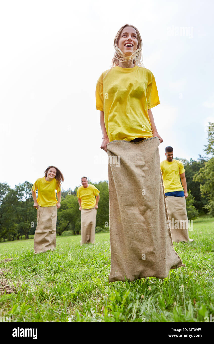 Young sporty woman with her team makes sack races at a competition ...