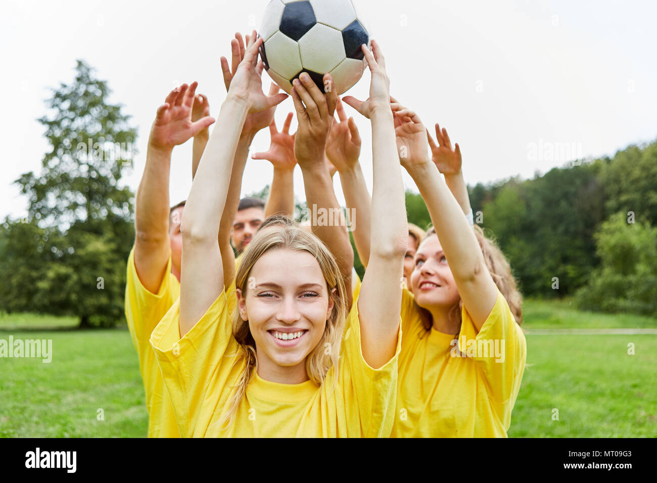 Young woman and her team are doing teamwork training with the football ...