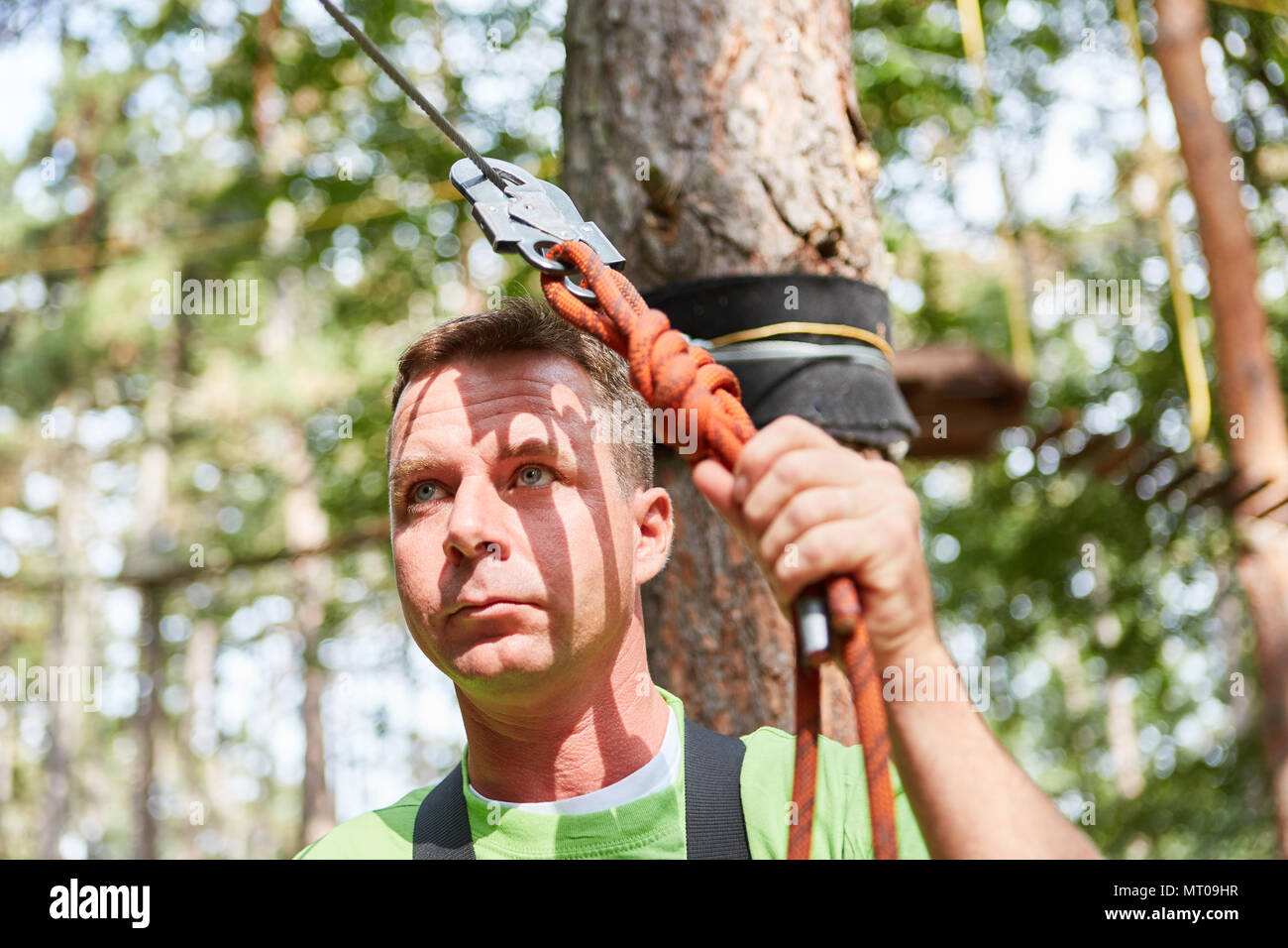 Young man at the start in high wire garden looks anxious and holds rope ...
