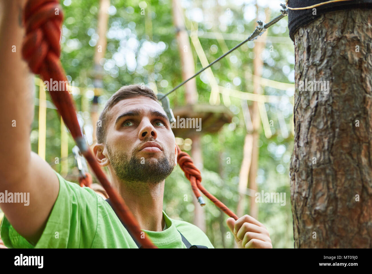 Climbing Beginners in the high ropes course carefully check the safety ...