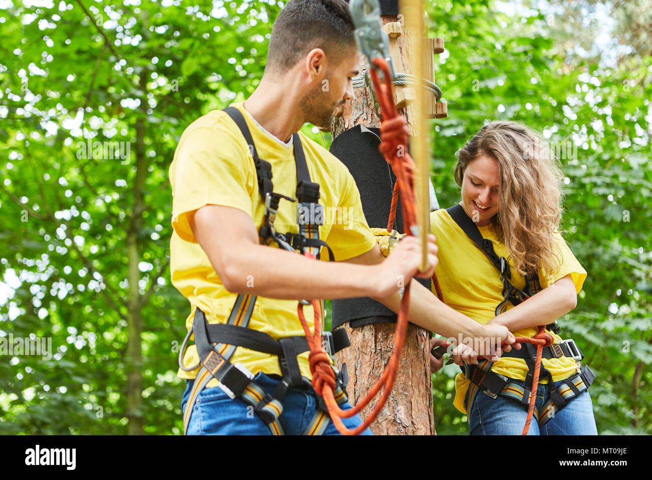 Woman and man in the high ropes course help themselves with the ...