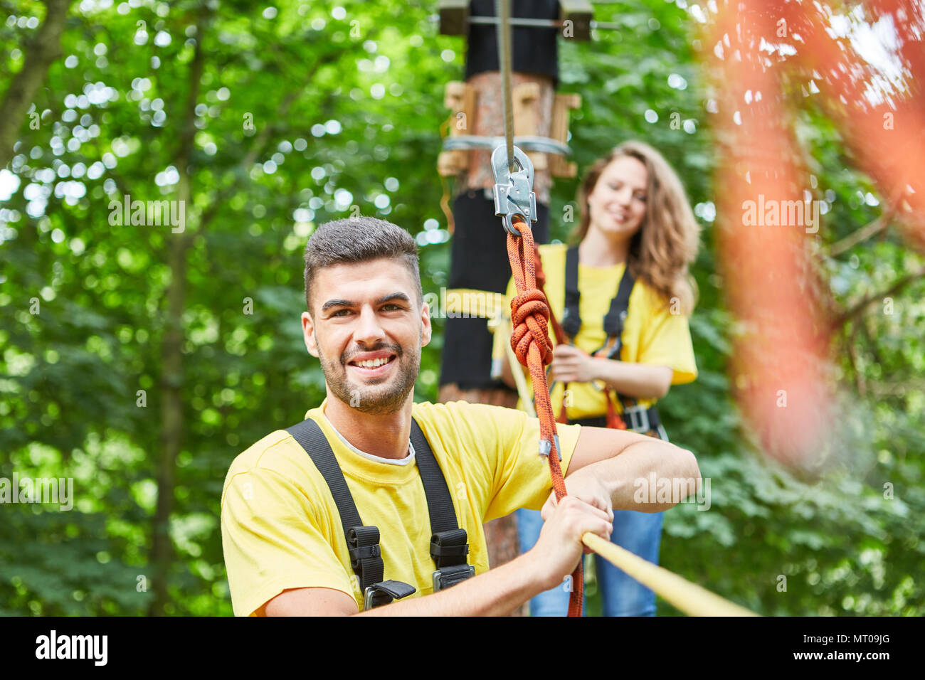 Young man in high wire garden secured with rope is proud of his ...