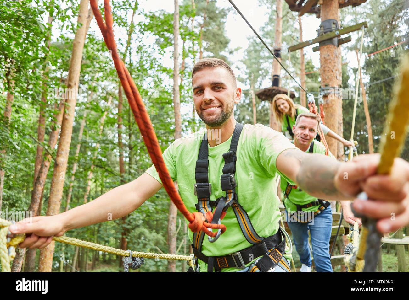 Man and his team climbing in the high wire garden at the team training ...