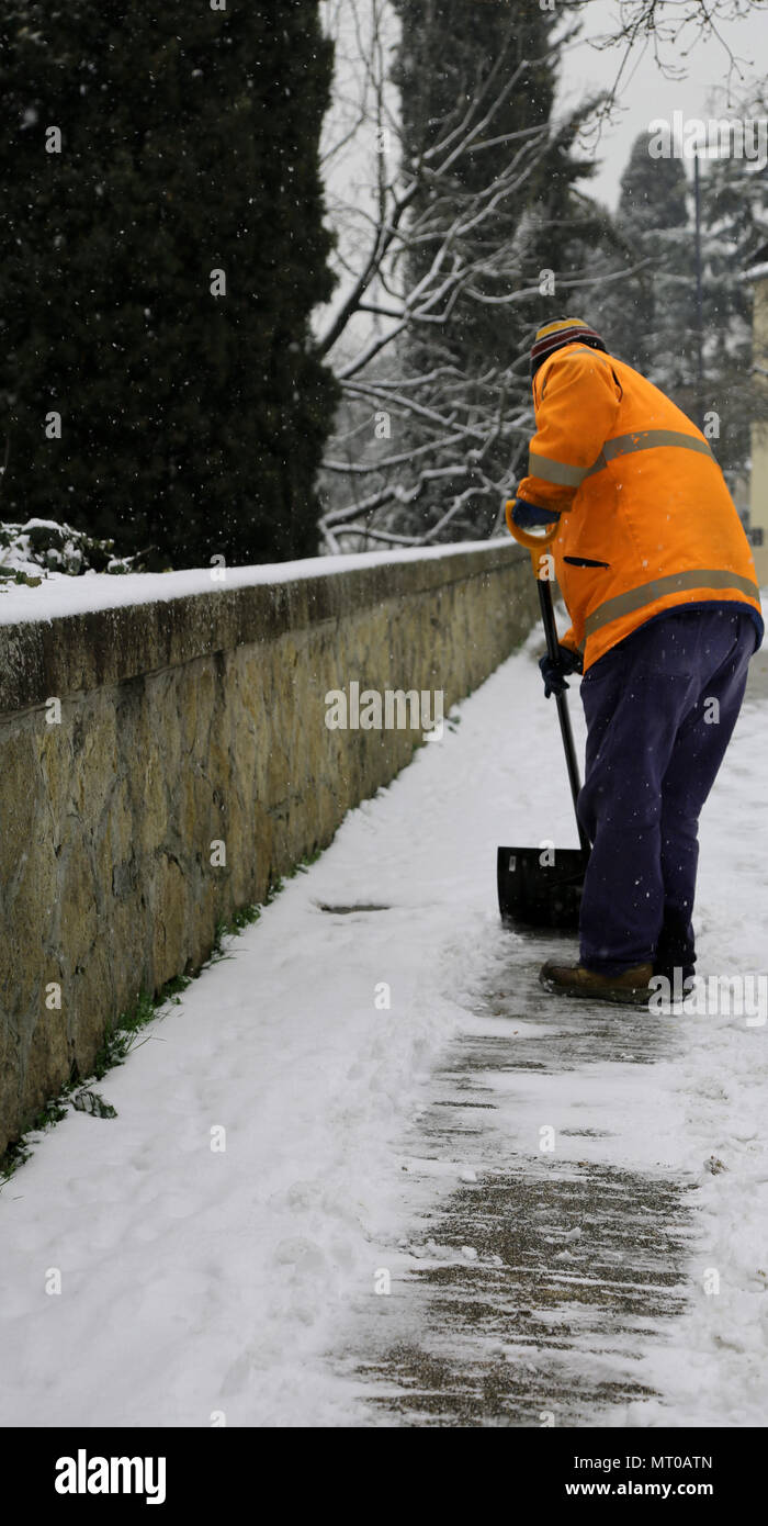 worker with high visibility jacket while shoveling snow from frozen ...