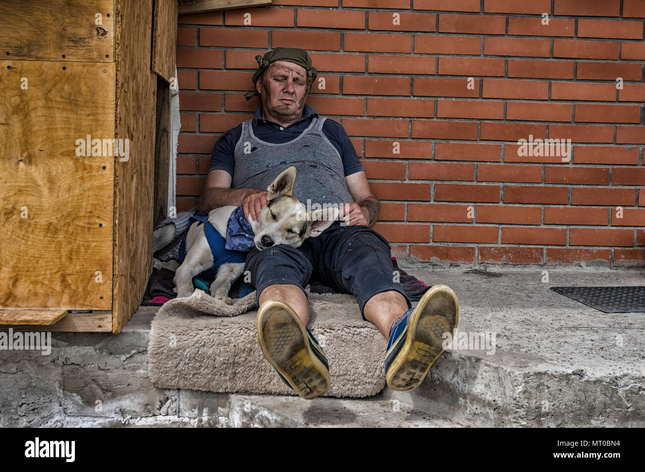 Two homeless fiends - man and dog sleeping while sitting on a concrete ...