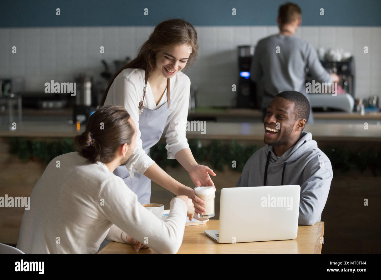 Waitress and multiracial visitors laughing at funny joke in cafe Stock ...