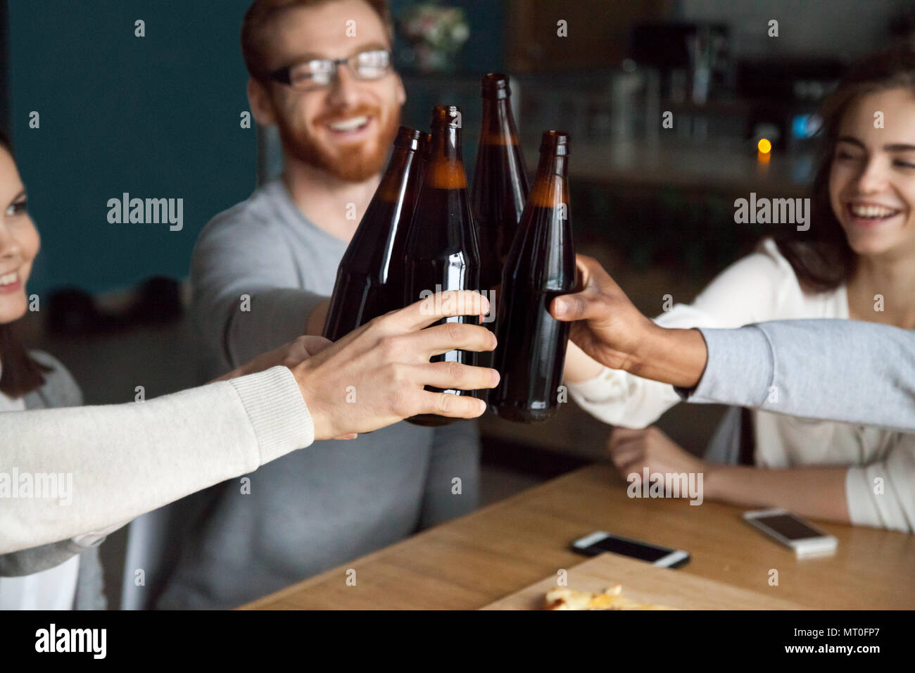 Diverse friends clinking craft beer bottles in pub, cheers conce Stock ...