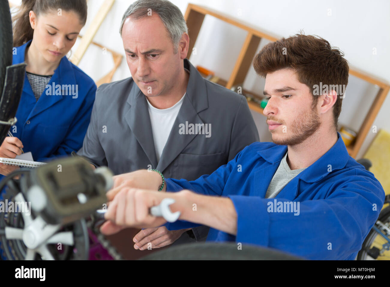 Student using spanner, teacher observing Stock Photo - Alamy