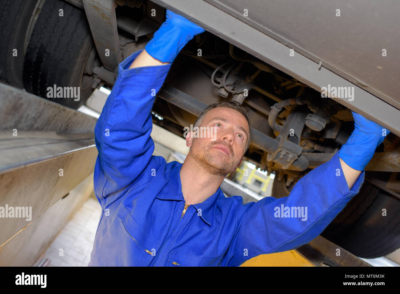 Mechanic in pit checking underneath of vehicle Stock Photo - Alamy