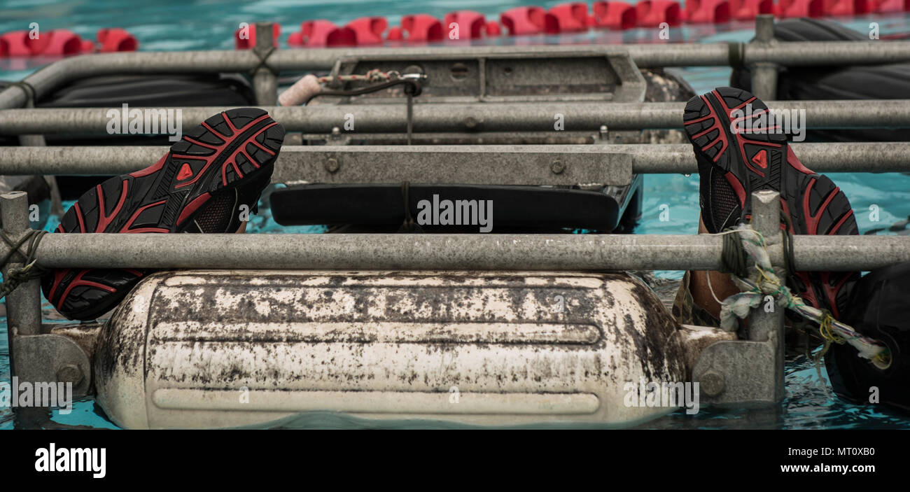 An aircrew member lies submerged in a shallow water egress trainer ...