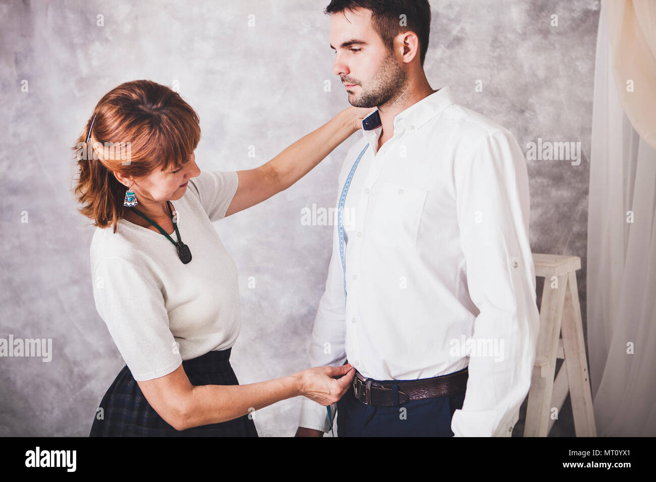 Woman tailor takes measures with male models. Mid section portrait of ...