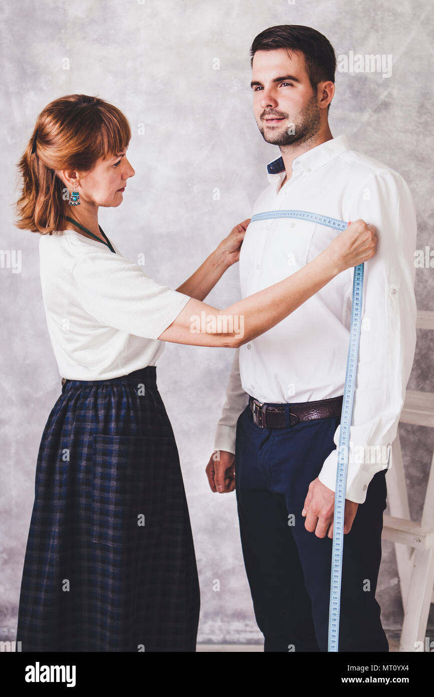 Woman tailor takes measures with male models. Mid section portrait of ...