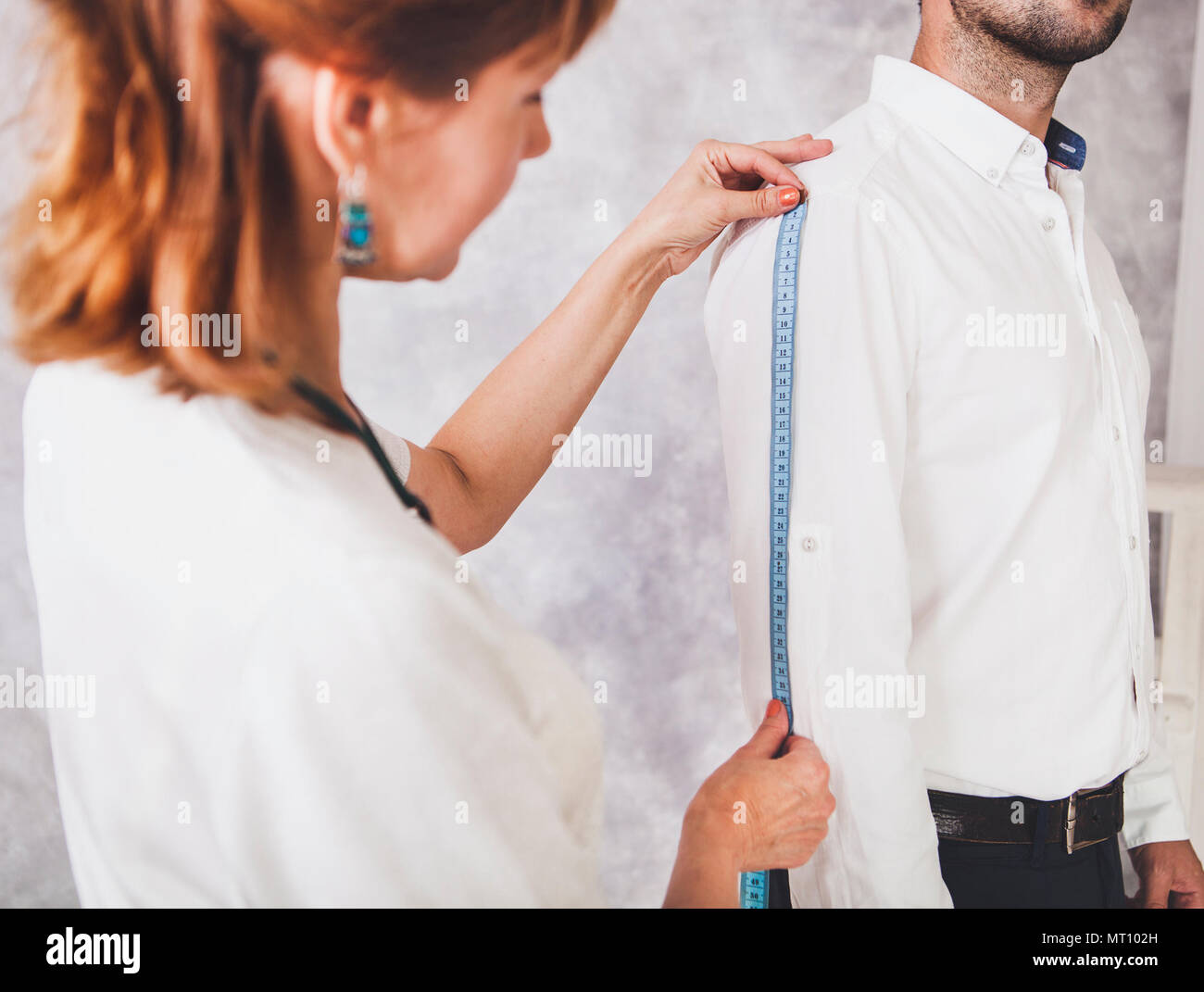 Woman tailor takes measures with male models. Mid section portrait of ...