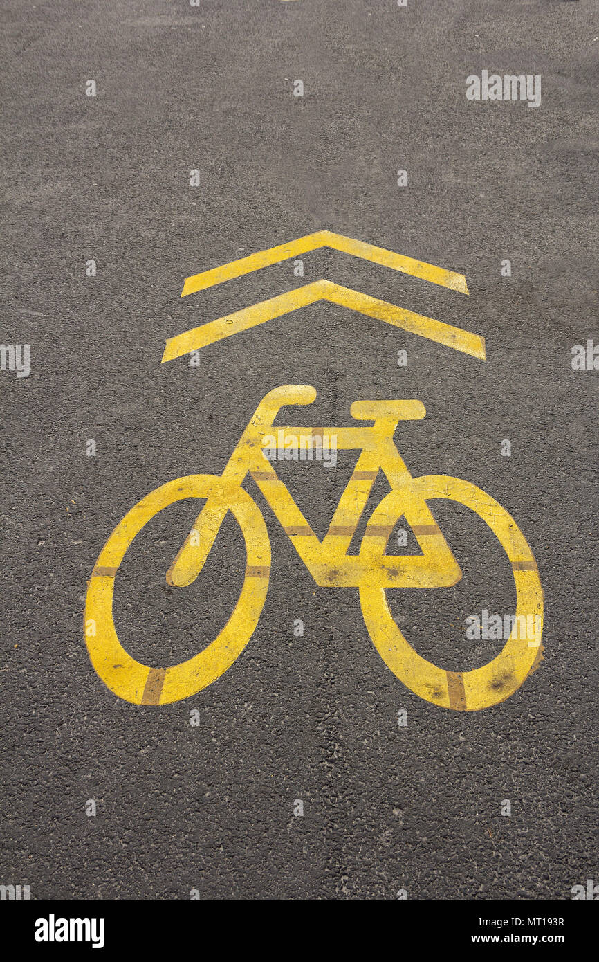 Yellow sign of a bicycle path drawn on the asphalt road. Lanes for ...
