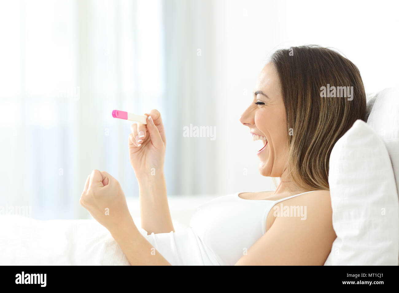 Side view portrait of an excited woman checking a positive pregnancy ...