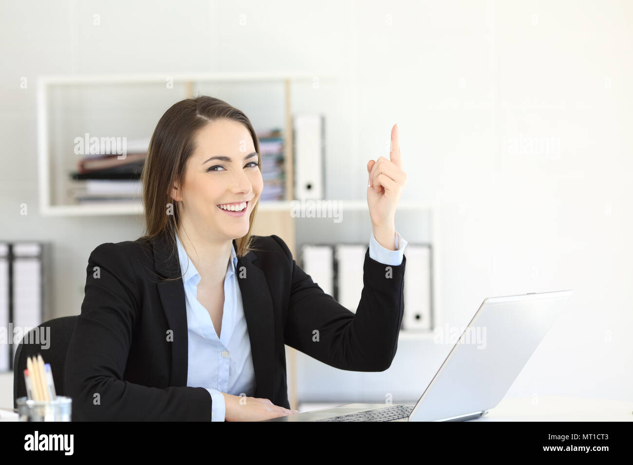 Happy office worker pointing up to a blank space and looking at camera ...