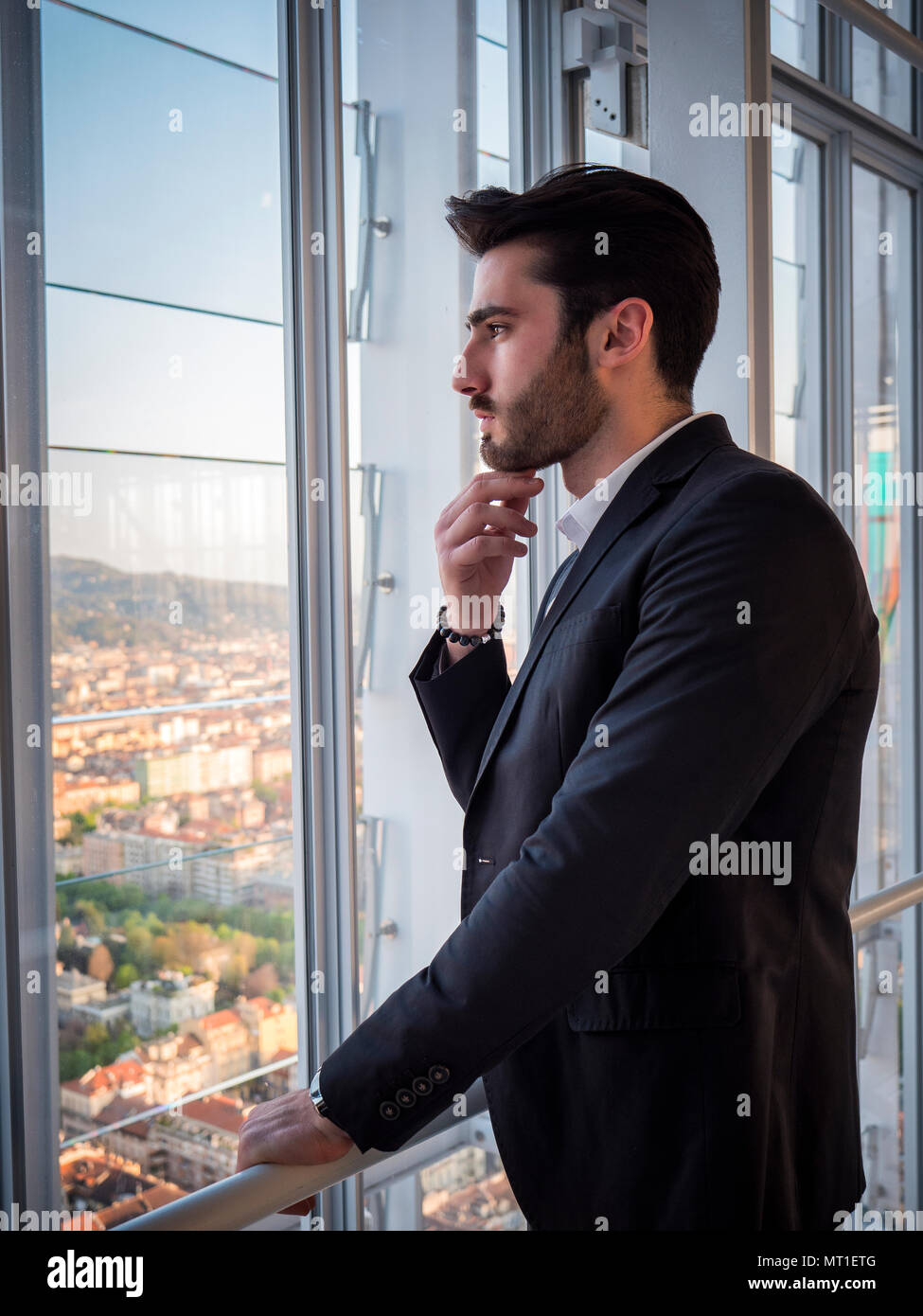 Handsome serious businessman standing inside modern building next to ...
