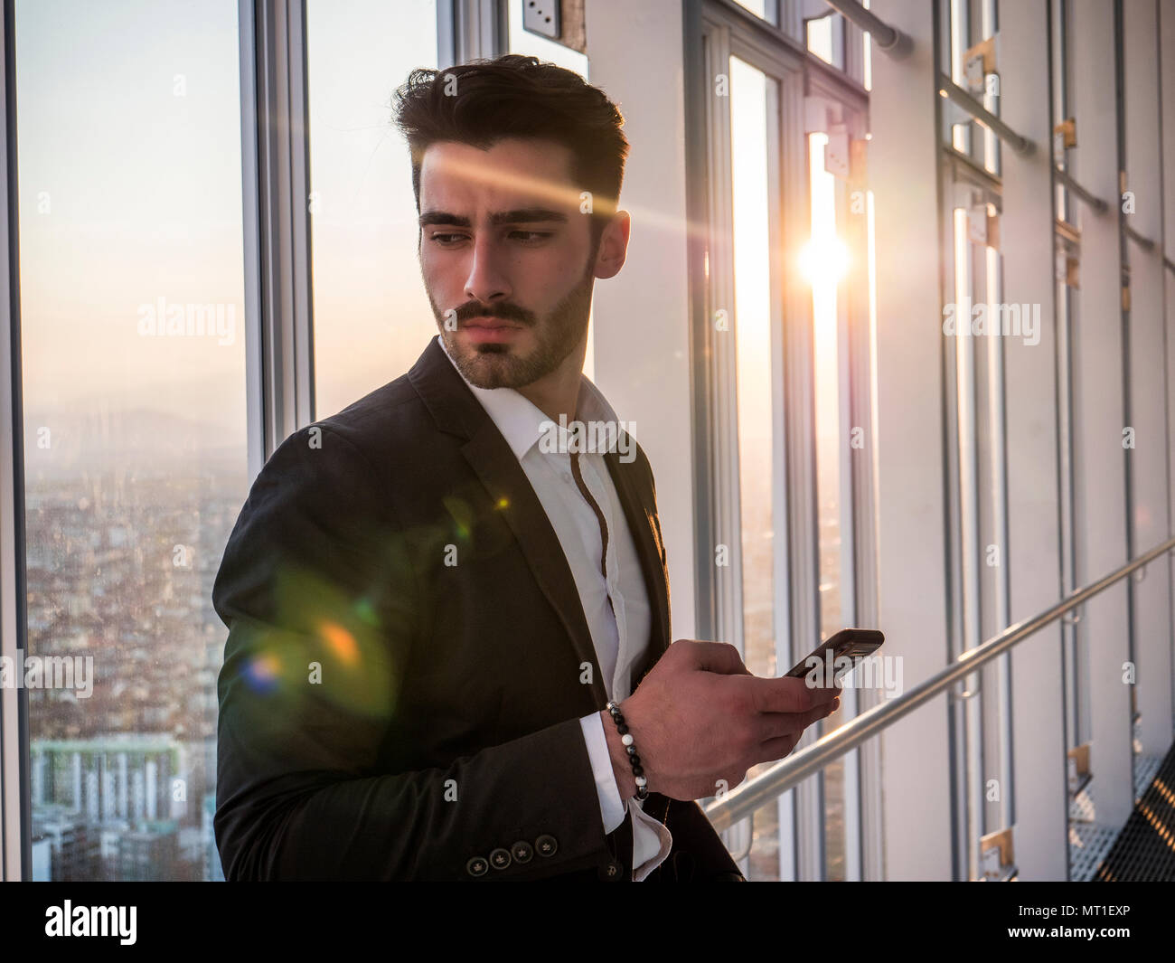 Handsome serious businessman standing inside modern building using ...