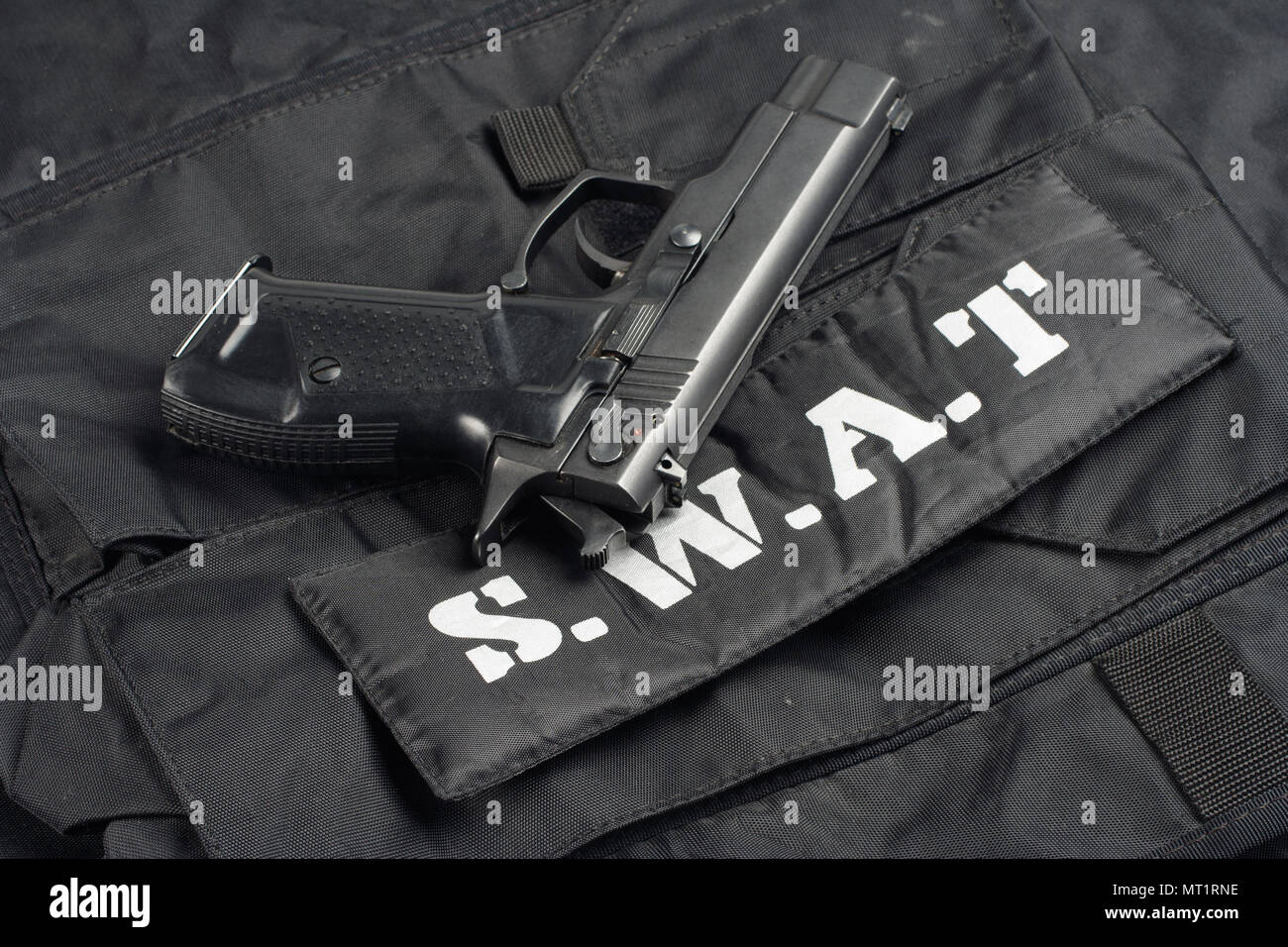 SWAT handgun on black uniform background Stock Photo - Alamy