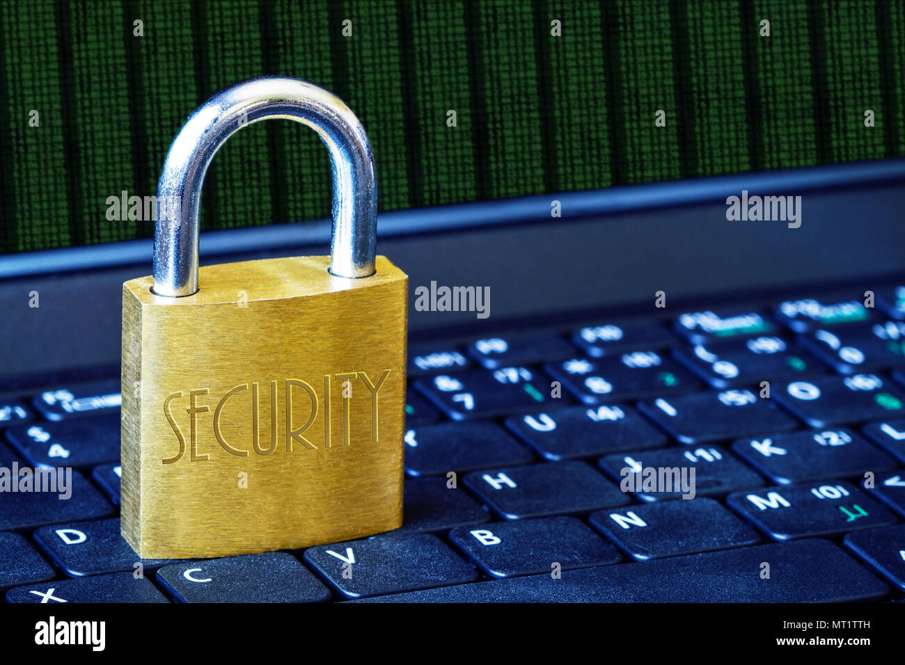 Golden padlock on computer laptop keyboard with binary data running and ...
