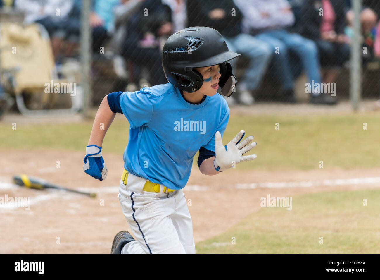 Little league batter hurrying up the first base line wearing helmet ...