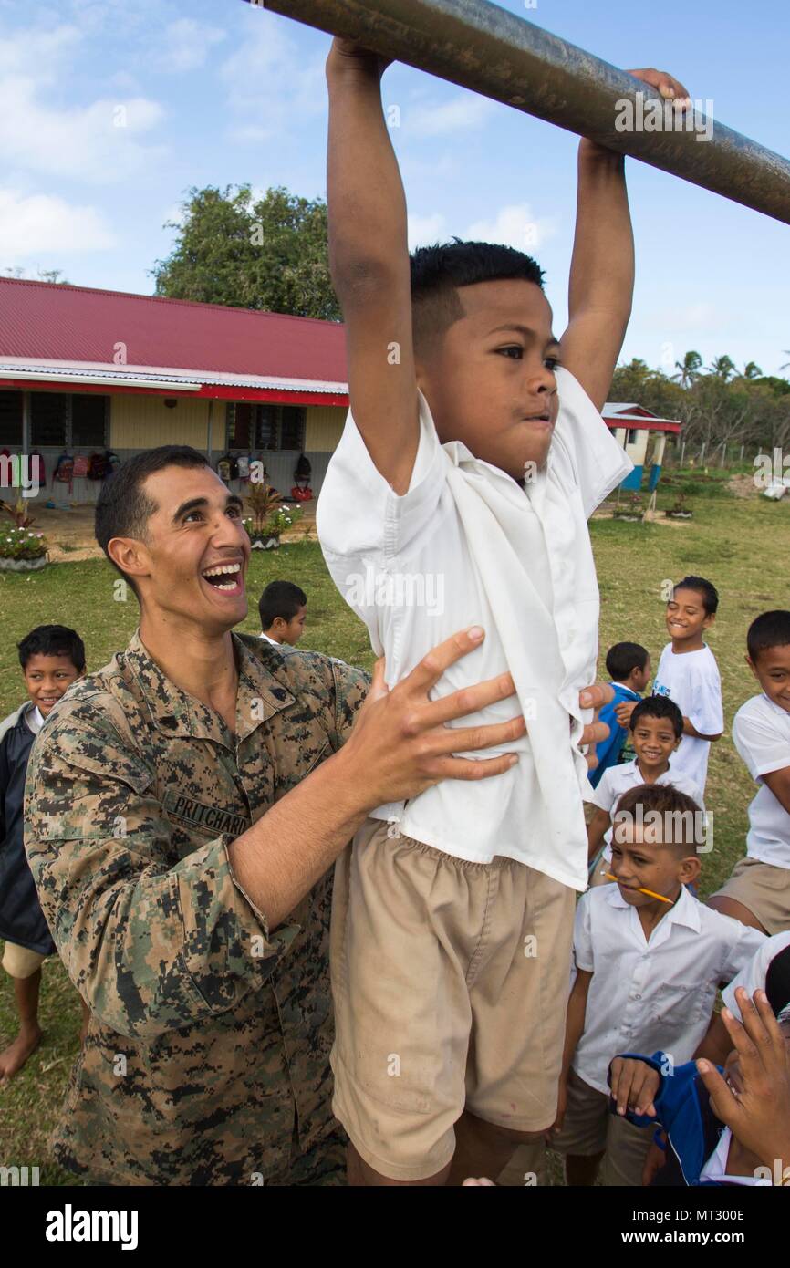 TONGATAPU ISLAND, Tonga — Sgt. Joseph Pritchard assists a child with ...