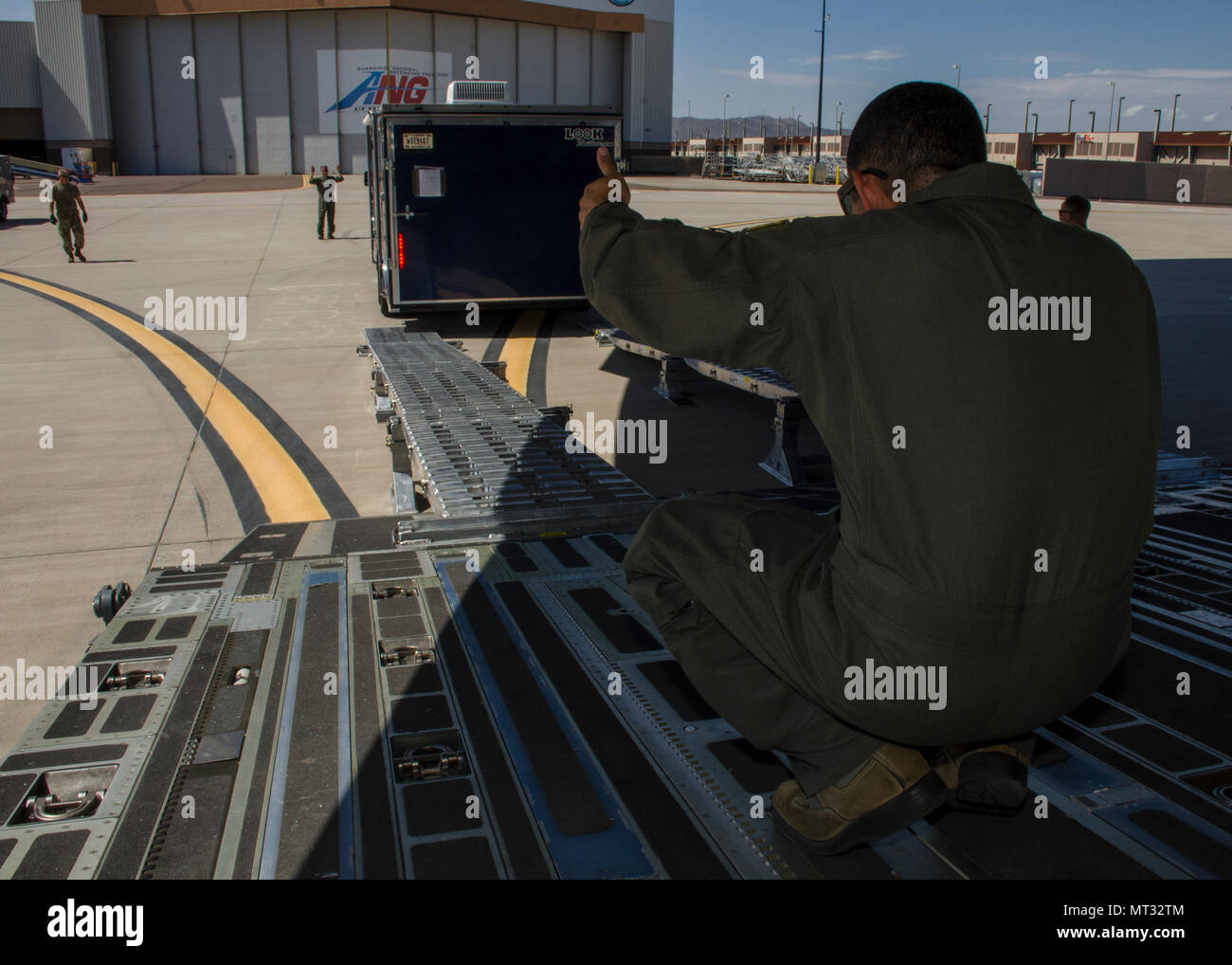 A loadmaster from the 452nd Airlift Wing guides a vehicle and trailer ...