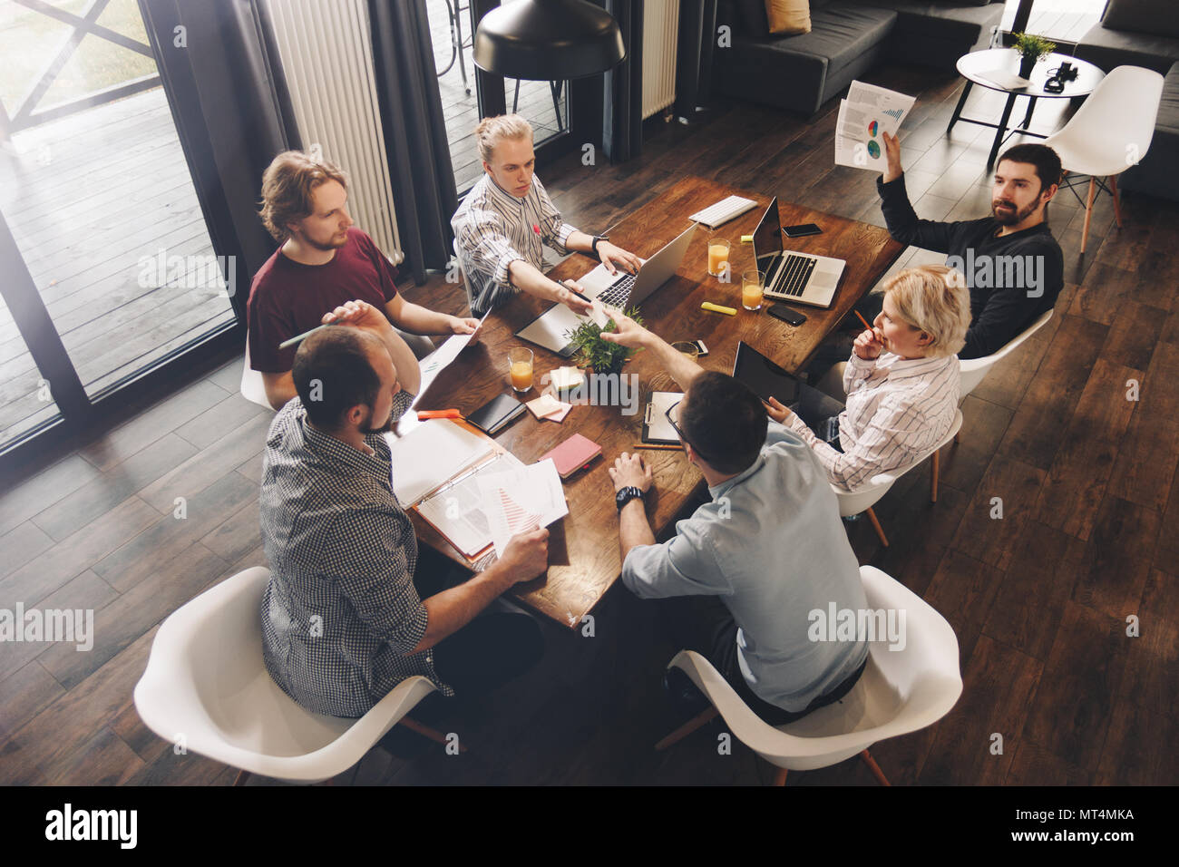Group of coworking people sitting around wooden table and working on ...